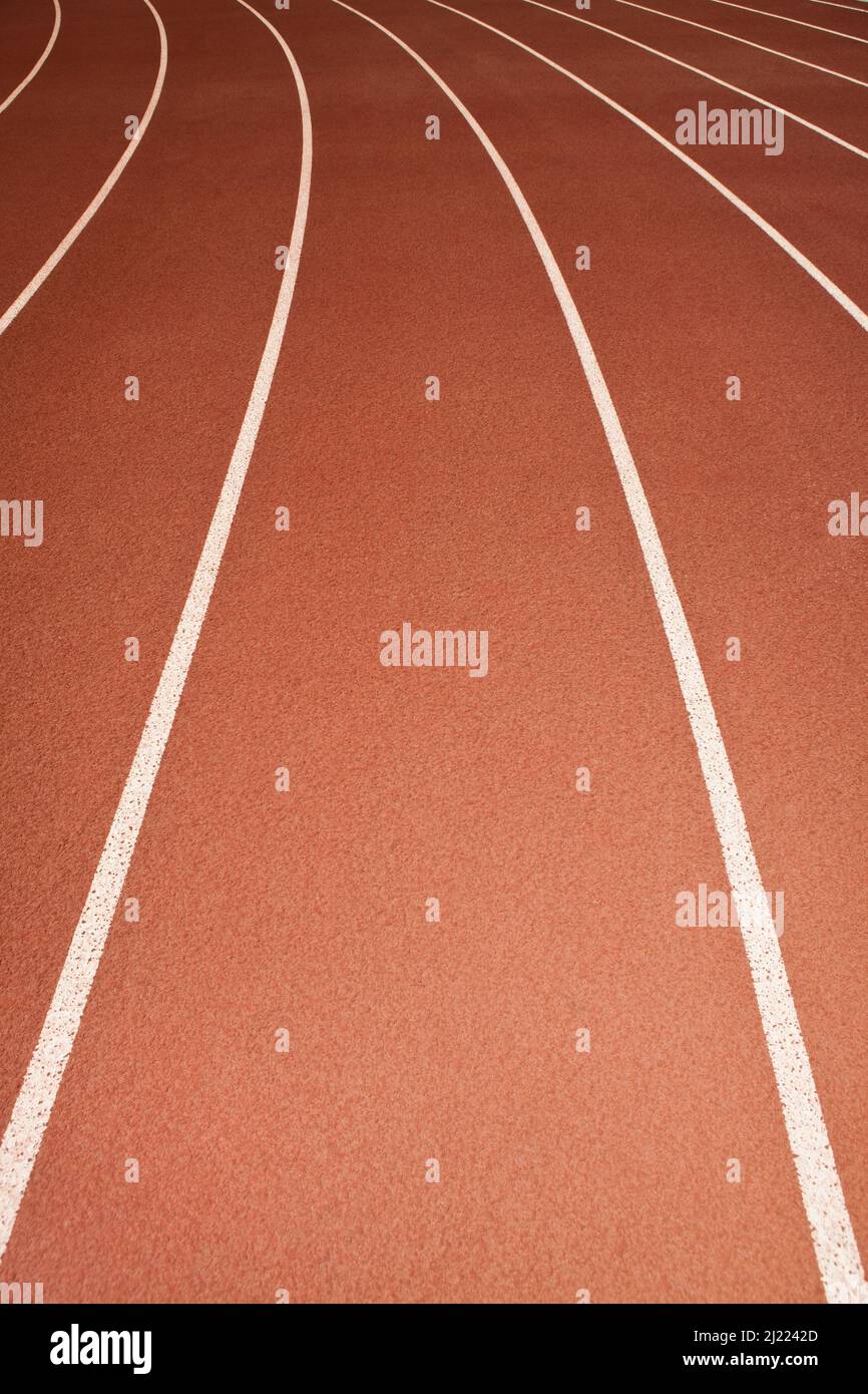 The surface of a sports athletics running track, red surface with white ...