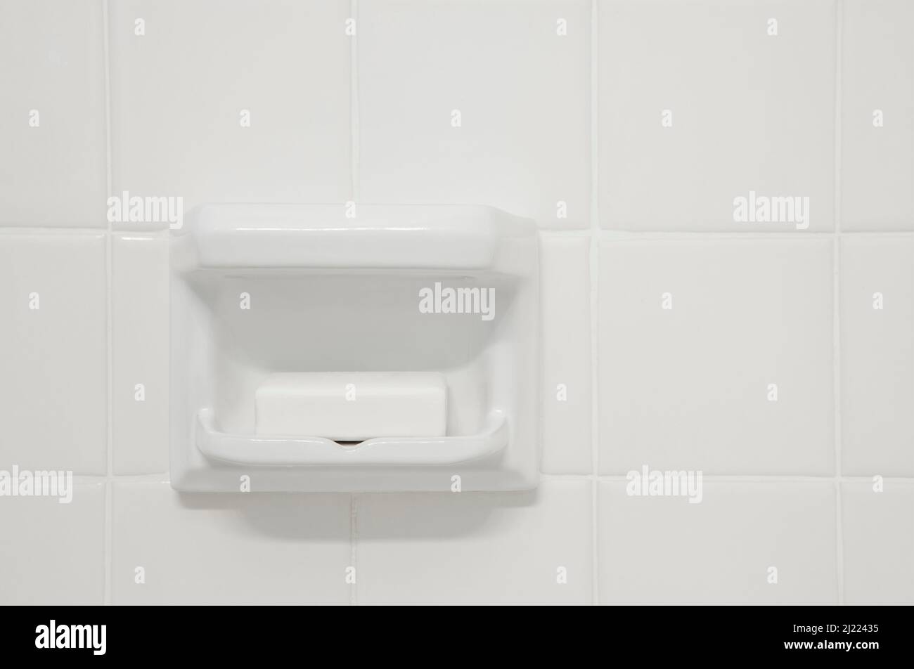 A white tiled wall of a bathroom or shower room,with a shaped porcelain ...