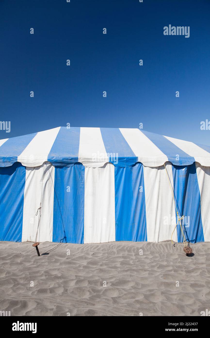 A large blue and white striped tent or marquee on a beach Stock Photo ...