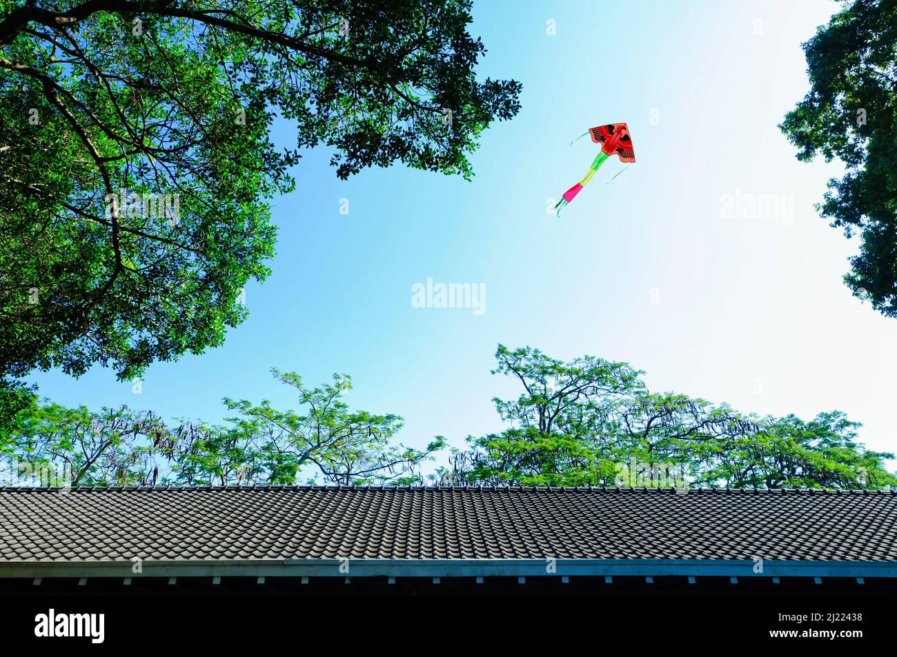 Colorful kite flying over traditional Chinese roof Stock Photo - Alamy
