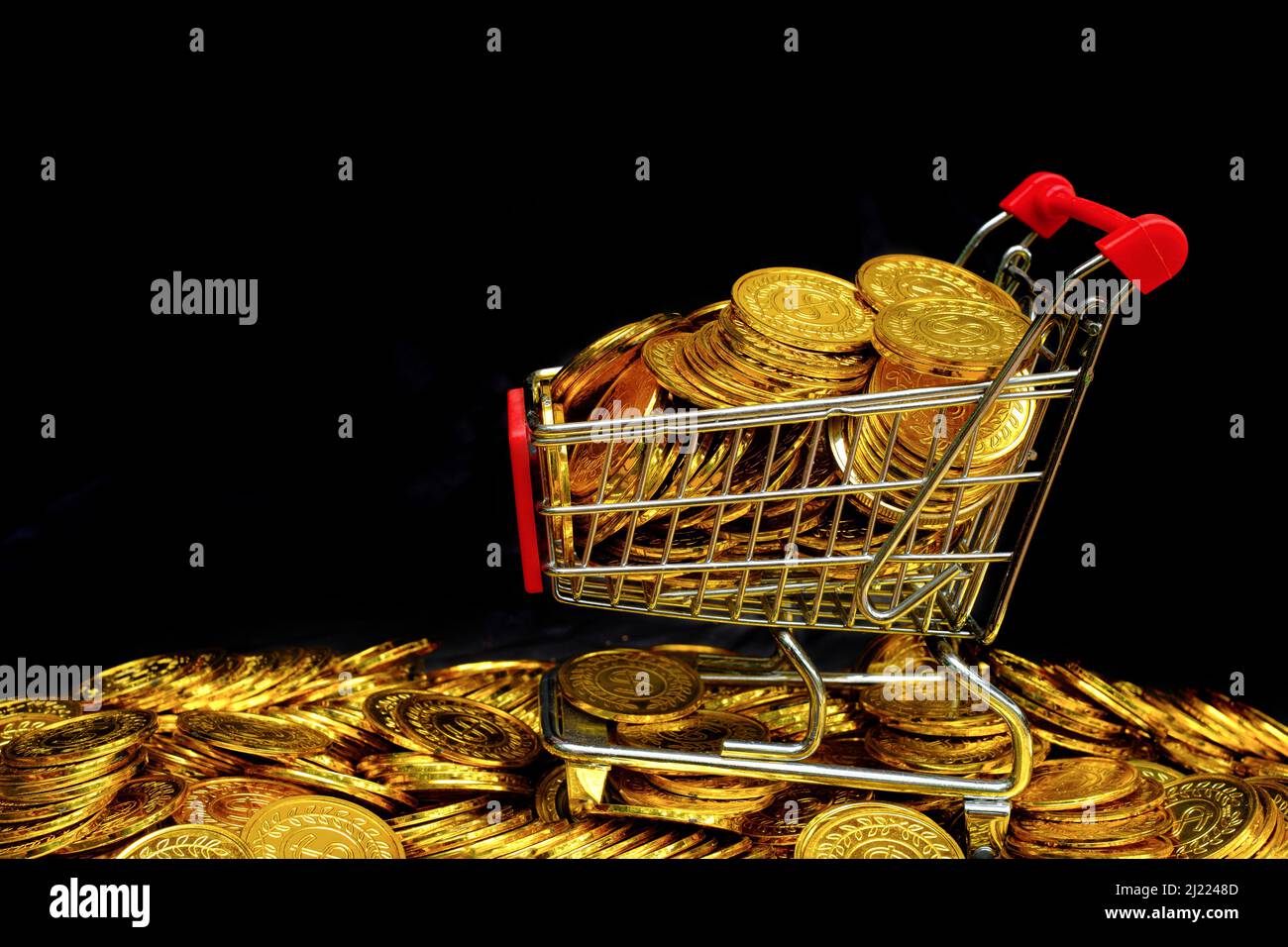 Golden coin in the shopping cart on a stacking gold coins at black ...