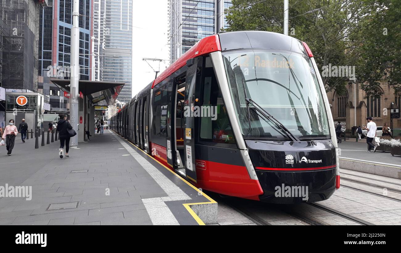 A red tram going through one of the streets in Sydney on a gloomy day ...