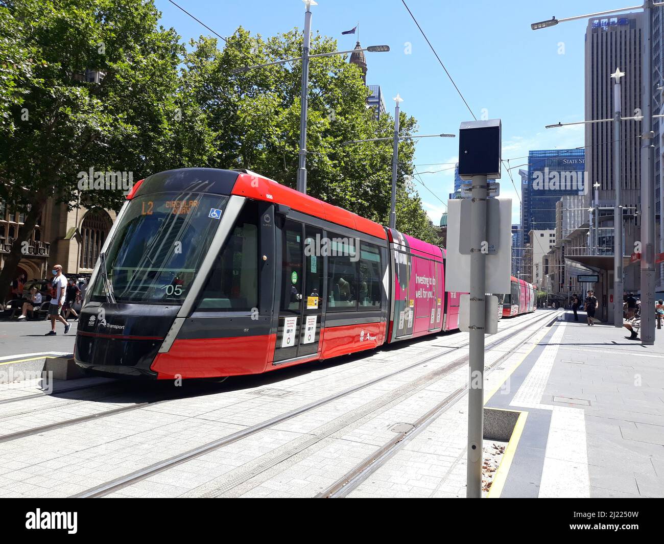 A red tram going through a street in the daytime in Sydney, Australia ...