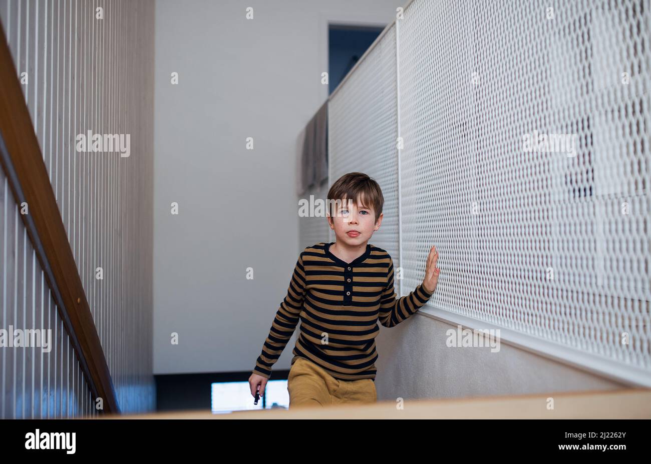 Little boy walking upstairs at home and looking at camera Stock Photo ...