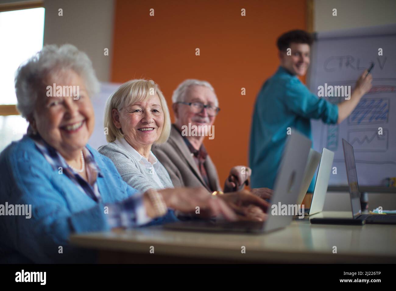 Senior group in retirement home with young instructor learning together ...