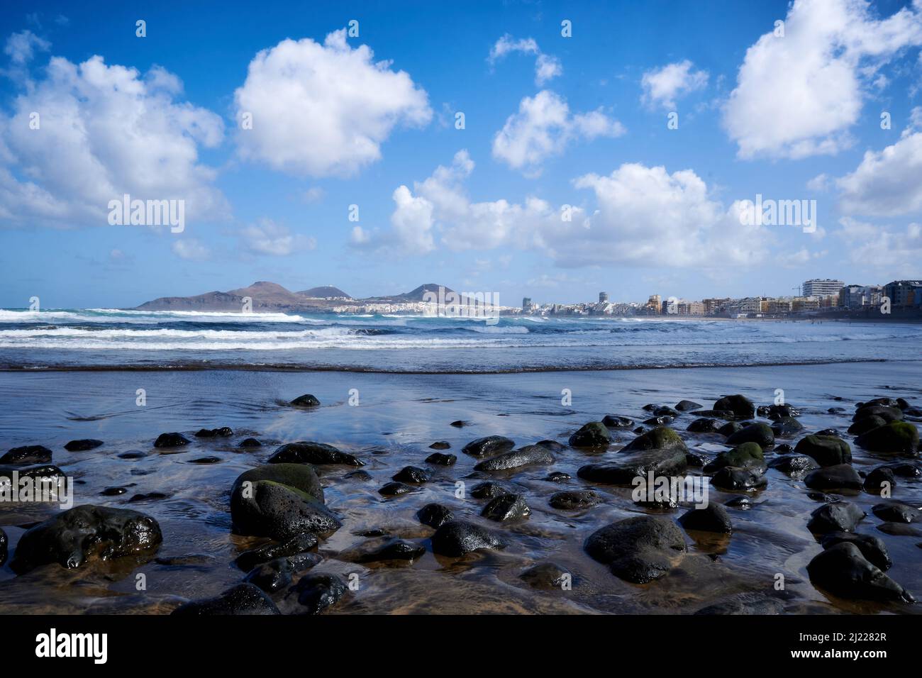 A scenic view of the Las Canteras rocky beach with waves reaching the ...