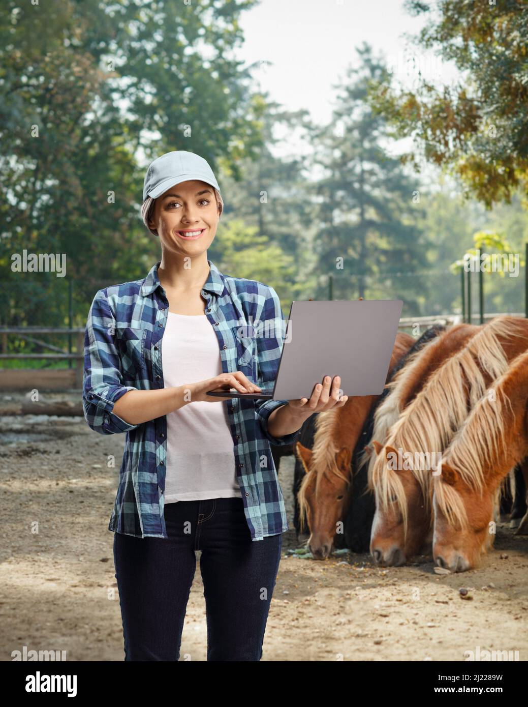 Modern female farmer with a laptop computer smiling and posing on a ...