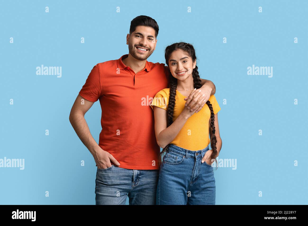 Romantic millennial arab couple posing together over blue studio ...
