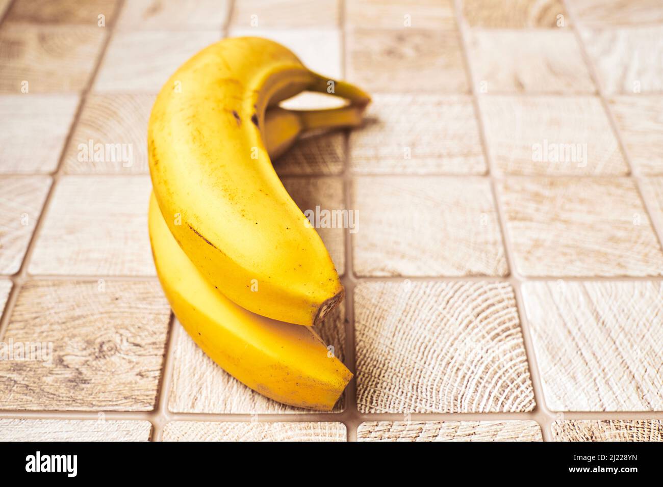 Two ripe bananas on a checkered wooden surface Stock Photo - Alamy