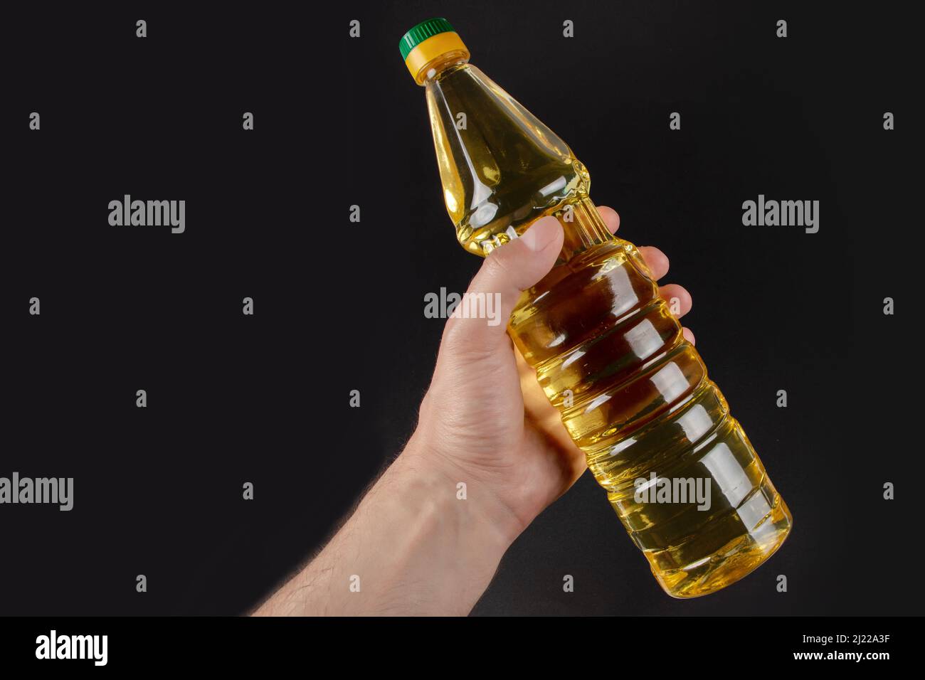 Hand with bottle of cooking oil on blsck background Stock Photo - Alamy