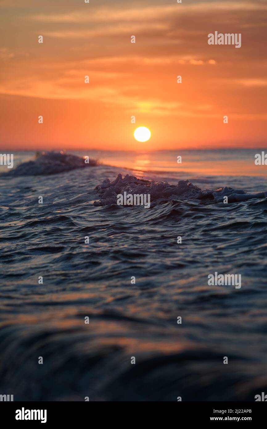 Focus on stormy sea surface with water splashes and foam at orange ...