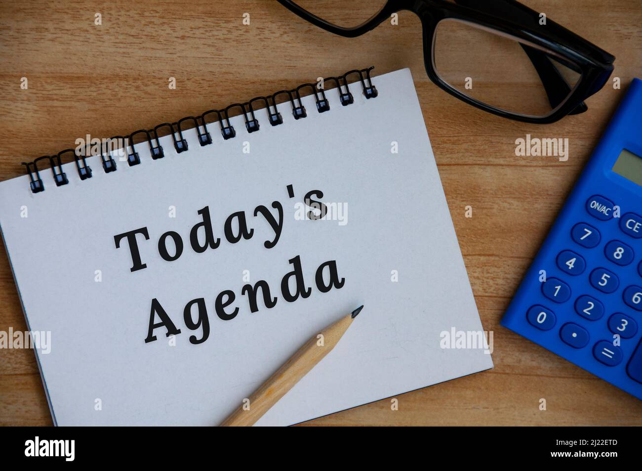 Today's agenda text on notepad. Glass, pencil and calculator background ...