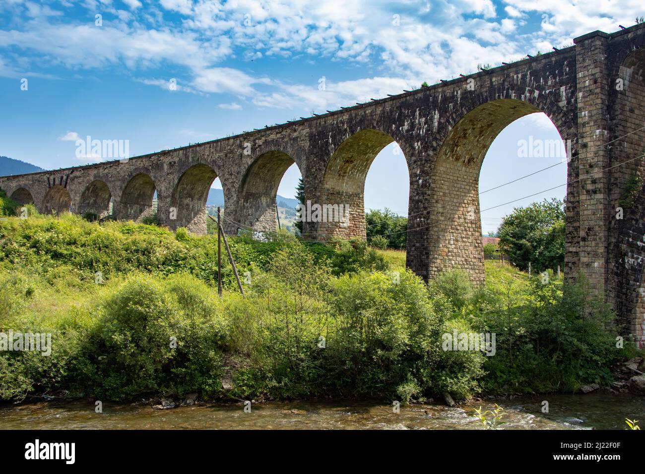 Arched viaduct in the mountains with a river Stock Photo - Alamy