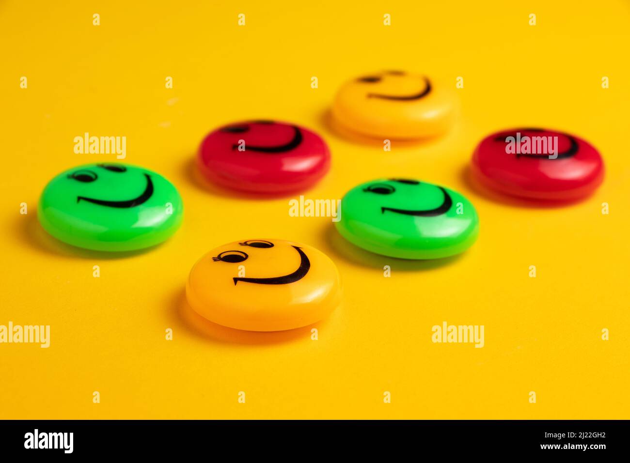 Green yellow and red round magnet with smile in a row on a yellow ...