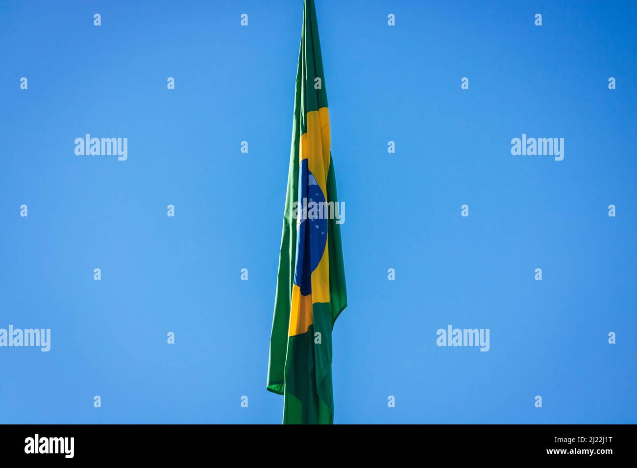 Concept image of a brazilian flag on pole without wind in front of blue ...