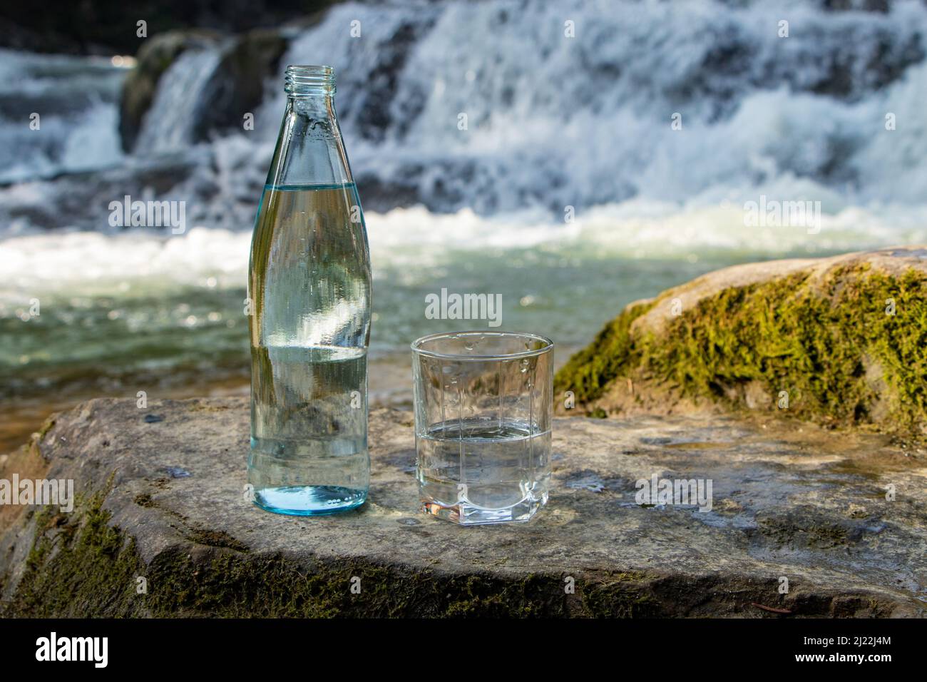 Natural drinking water in a bottle and glass beaker on nature ...
