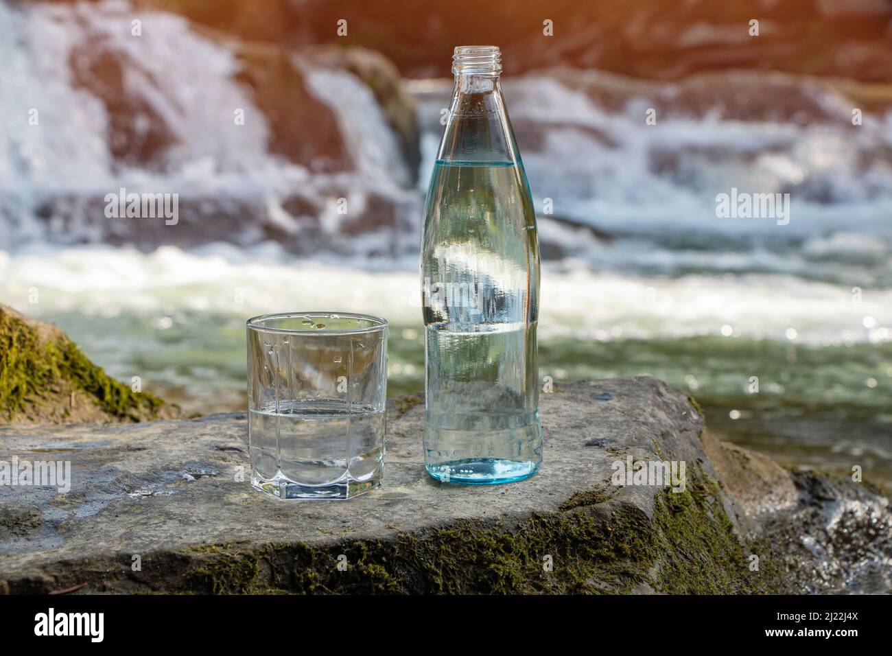 Natural drinking water in a bottle and glass beaker on nature ...