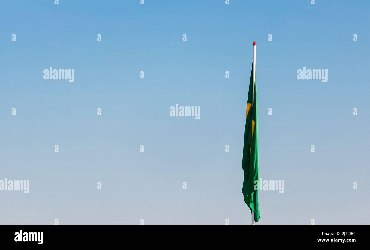 Concept image of a brazilian flag on pole without wind in front of blue ...