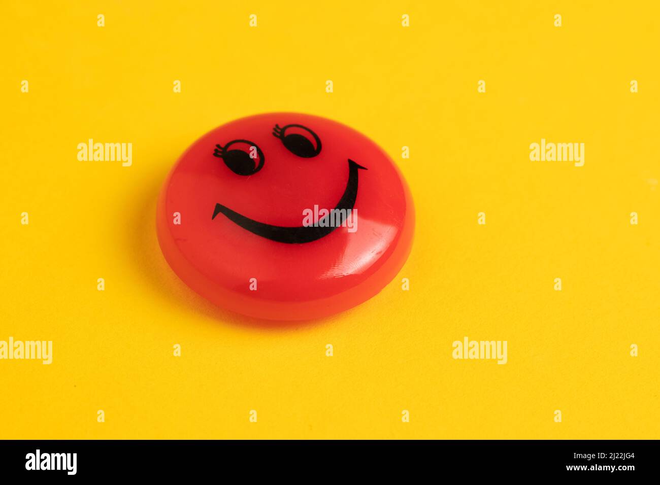 Red magnet smile - holders on a yellow background Stock Photo - Alamy