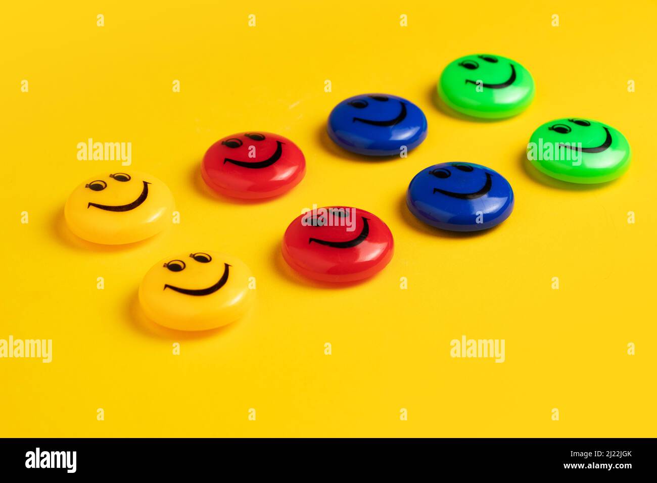Colorful magnets smile - holders on a yellow background Stock Photo - Alamy
