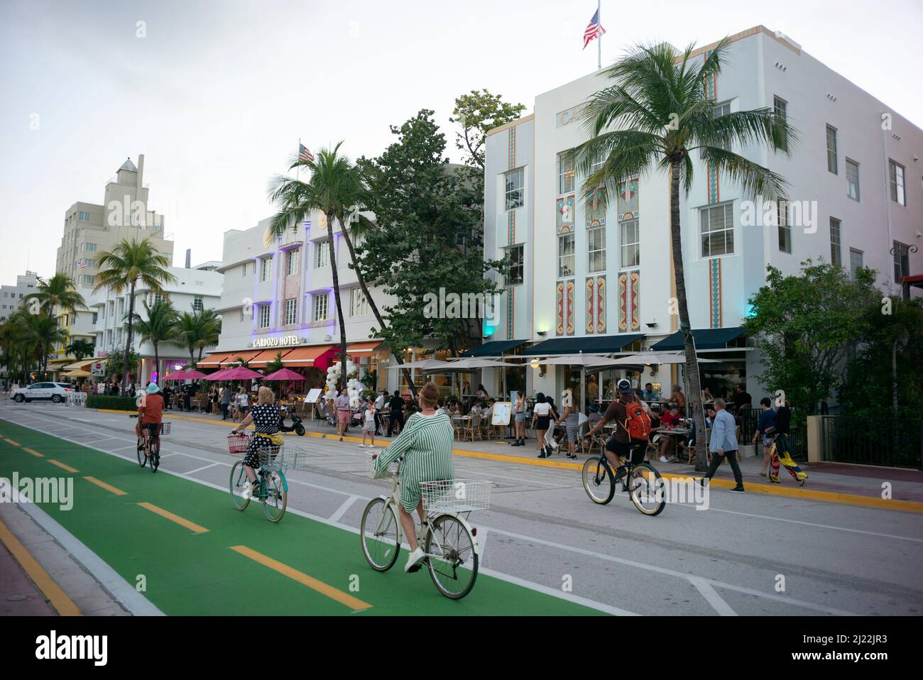 Mature Women riding bikes past Art deco buildings on Ocean Drive in ...