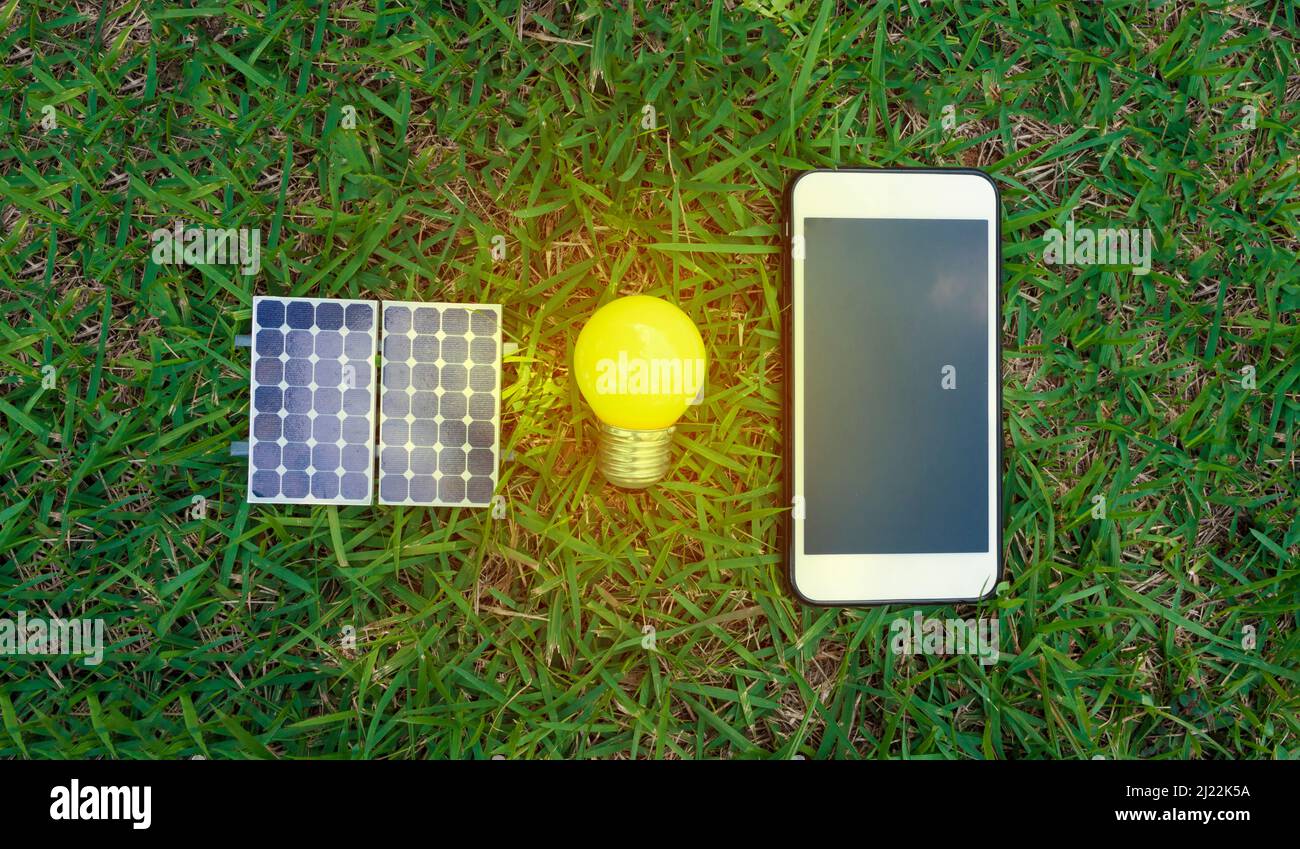 Photovoltaic solar panel, lamp, plug wire and mobile on green grass ...