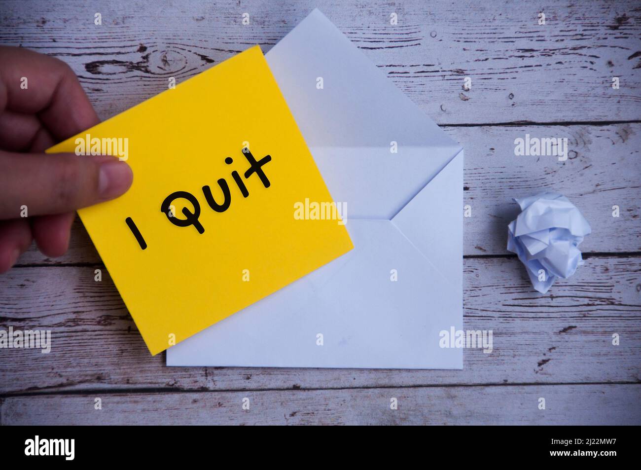 Hand holding yellow notepad with text - I quit with envelope background ...