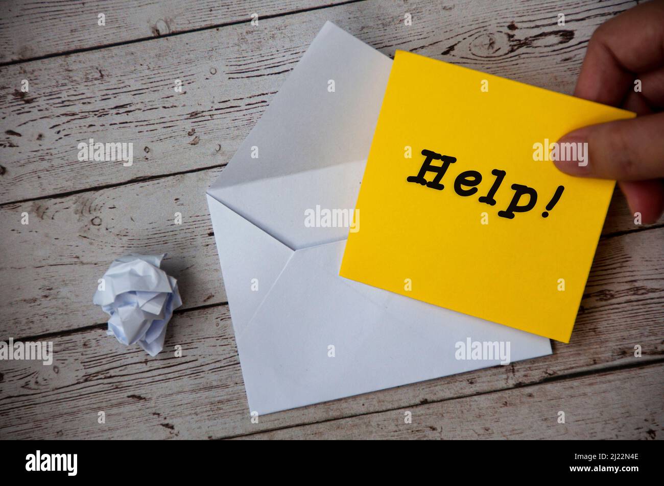 Hand holding yellow notepad with text - Help, with envelope background ...