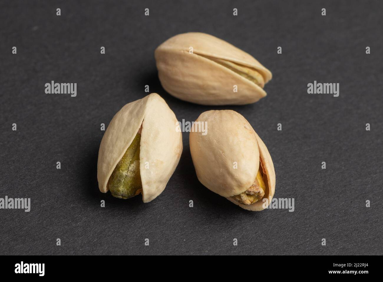 Peeled and unpeeled pistachios on dark background Stock Photo - Alamy