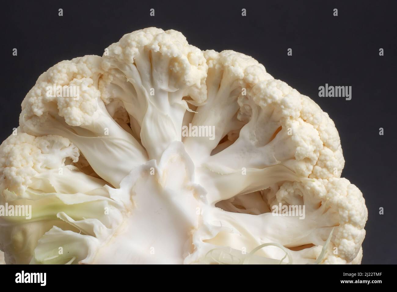 Ripe cauliflower with green leaves on dark background Stock Photo - Alamy