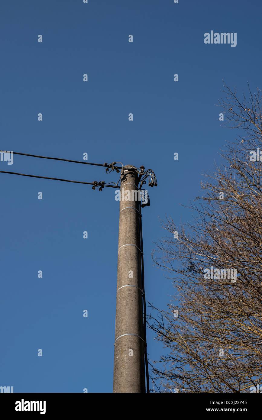 an electricity pylon made of concrete with twisted cables at clear blue ...