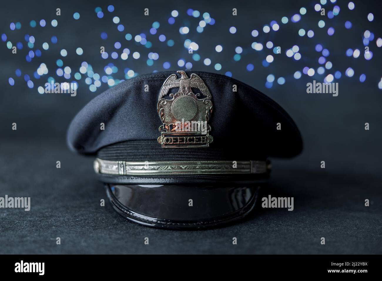 A navy blue police hat cap in front of a navy blue background with ...