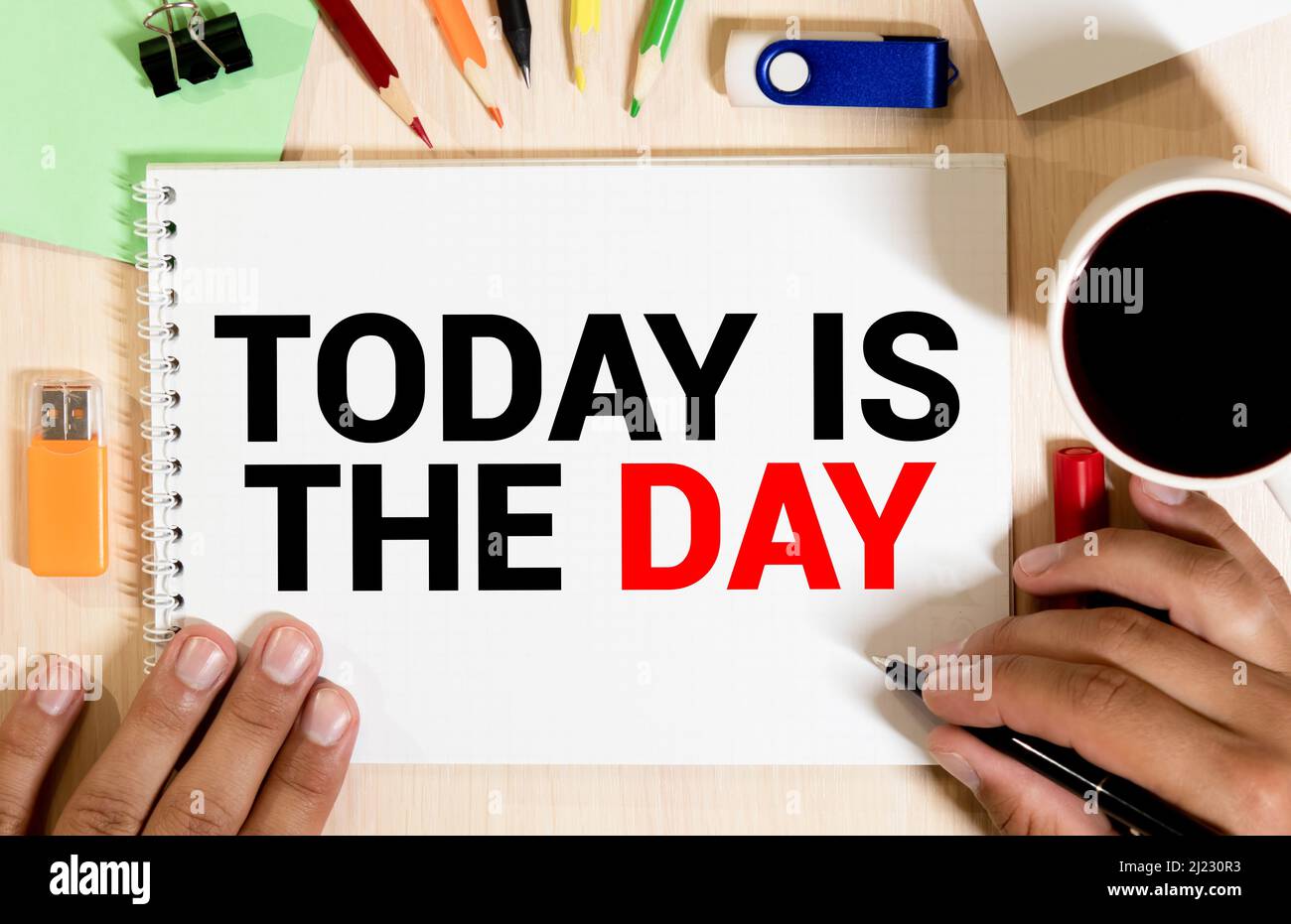 Hand holding a diary with the words, TODAY IS THE DAY printed on it ...