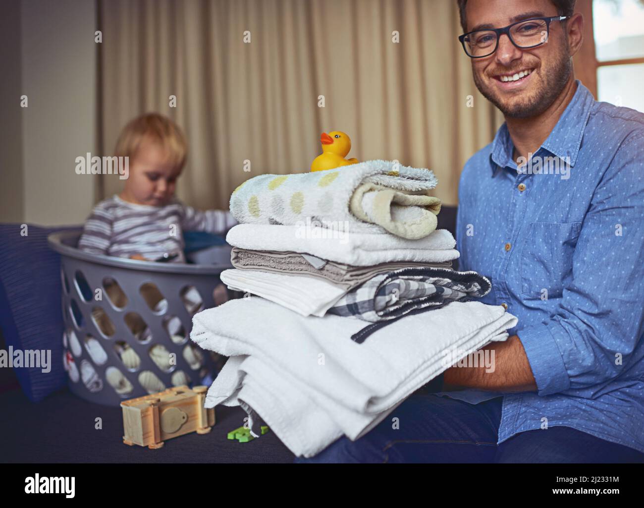 Dad does it all. Portrait of a young man holding a load clean laundry ...