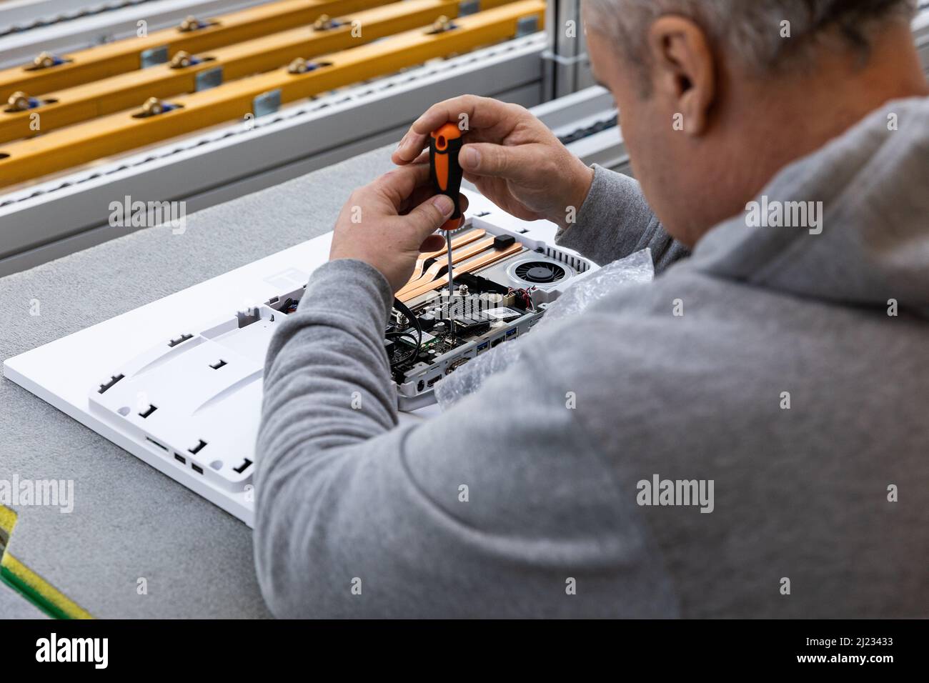 Photo of an adult man in a gray sweater who assembles a computer ...