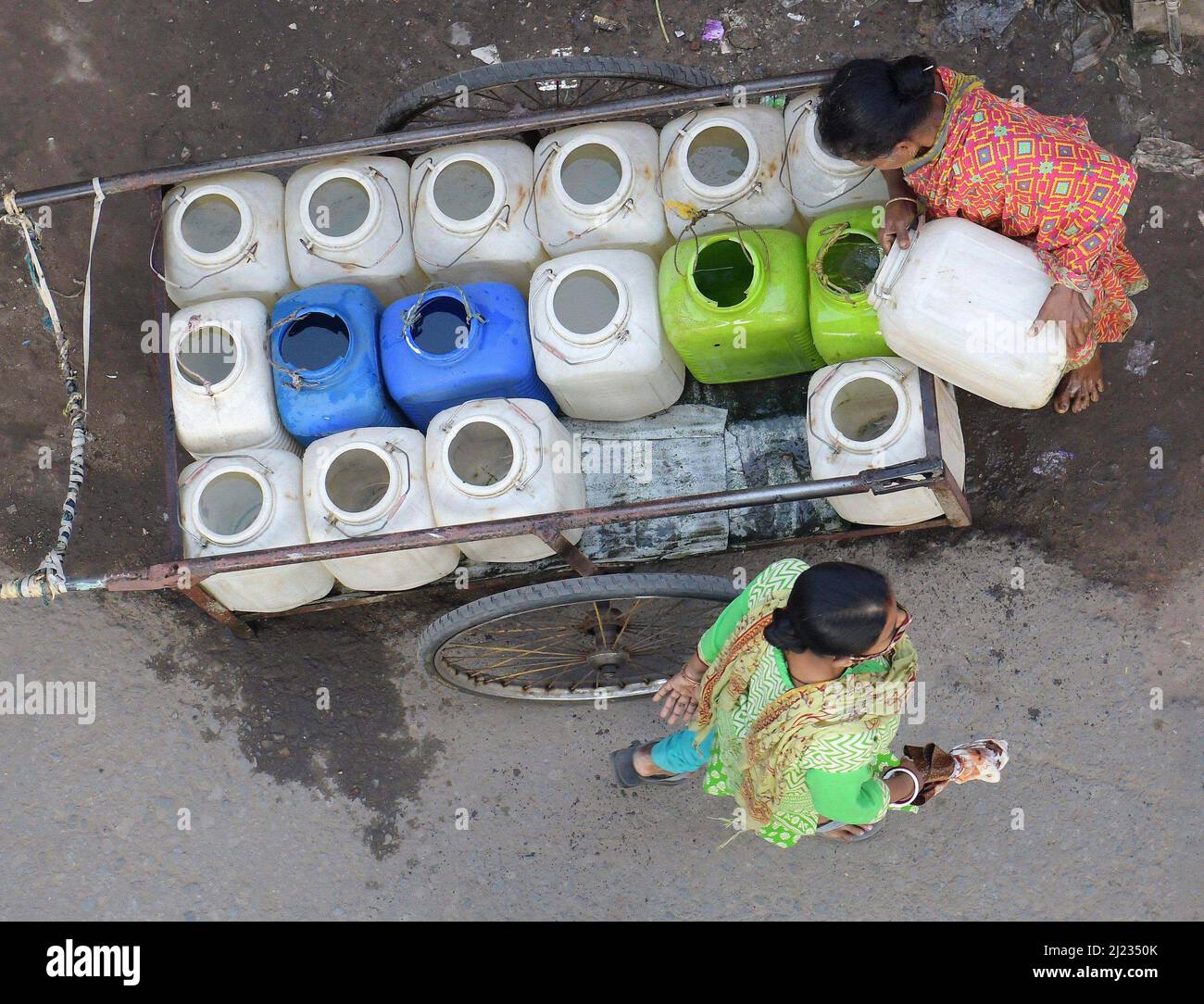 A worker fills plastic barrels with water for distribution to roadside ...