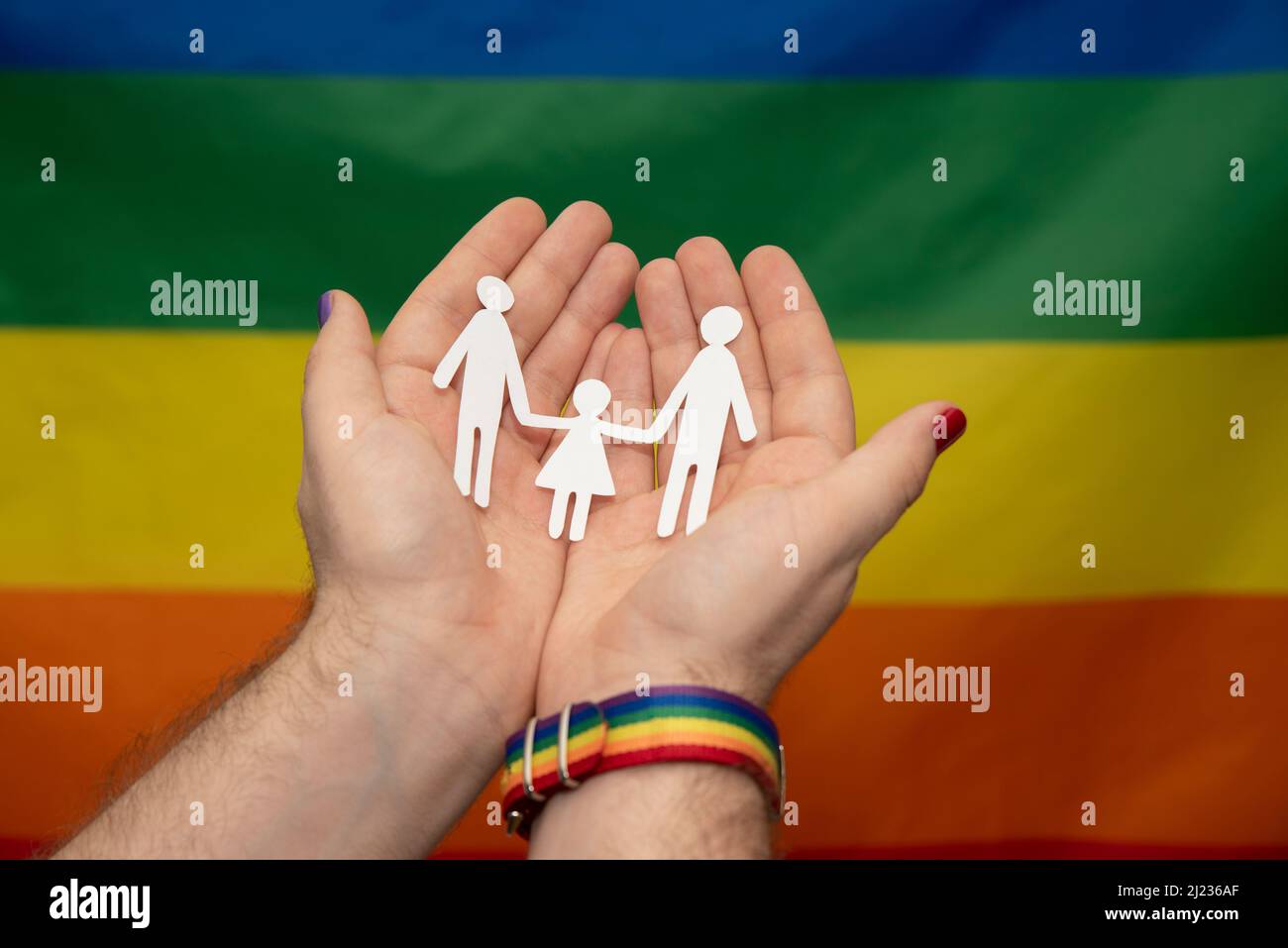 hands of man with gay paper family on lgtb rainbow flag background ...