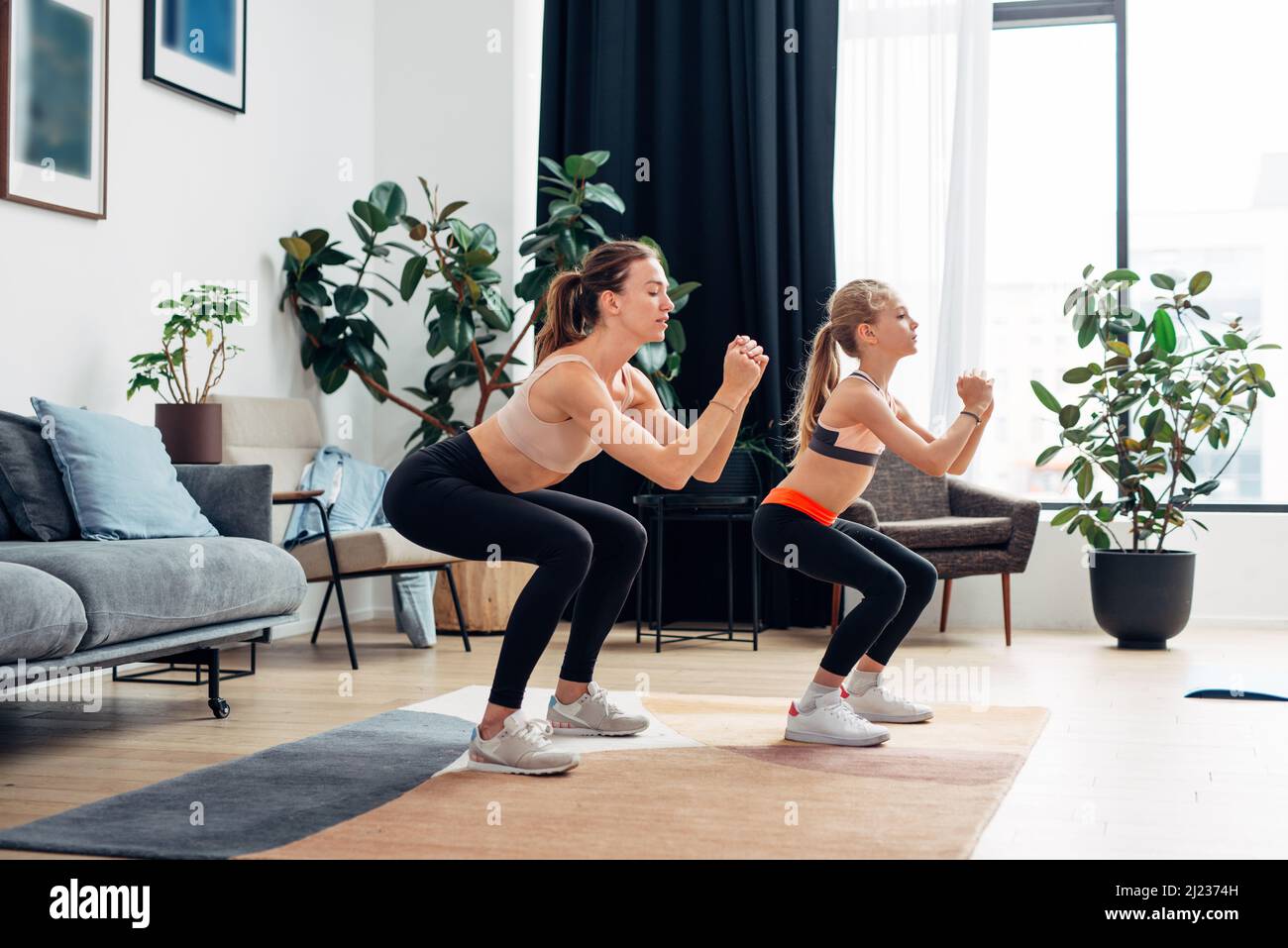 Mother and daughter doing squats. Home training Stock Photo - Alamy