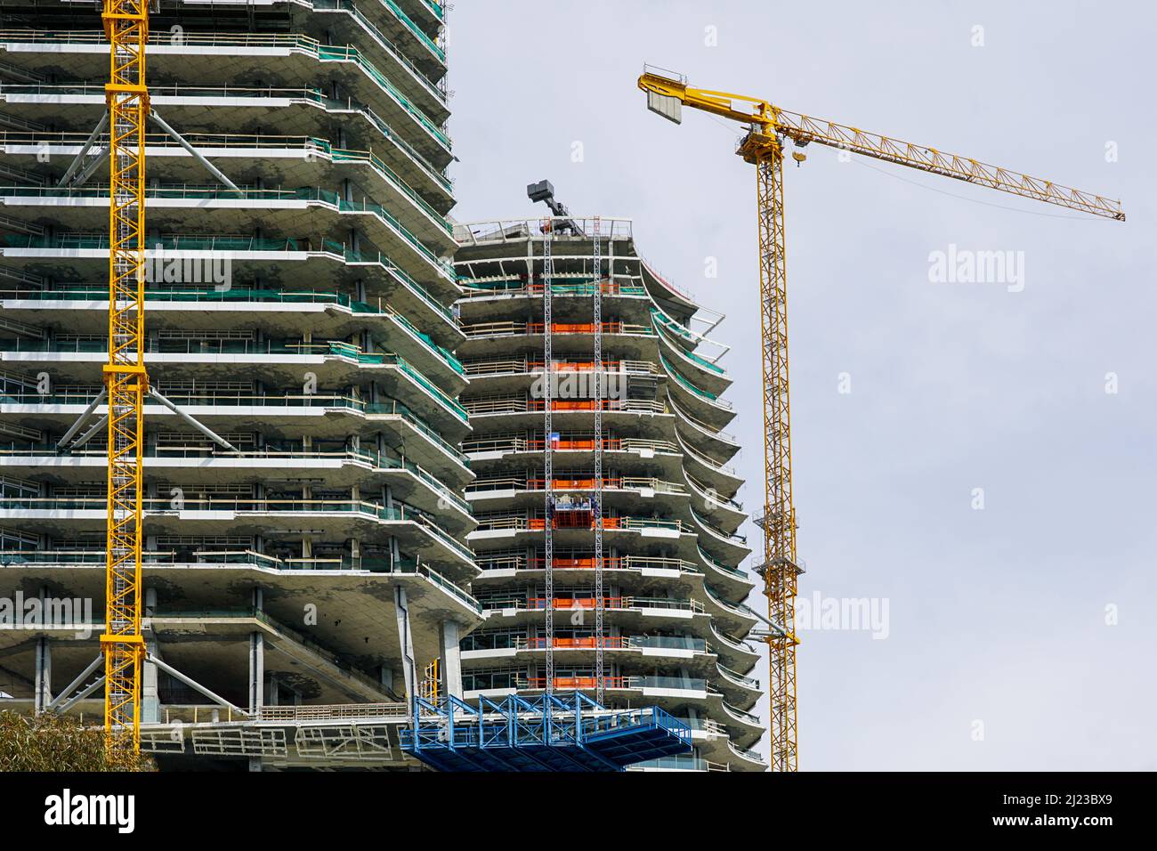 yellow tower crane and a fragment of the facade of an unfinished cement ...