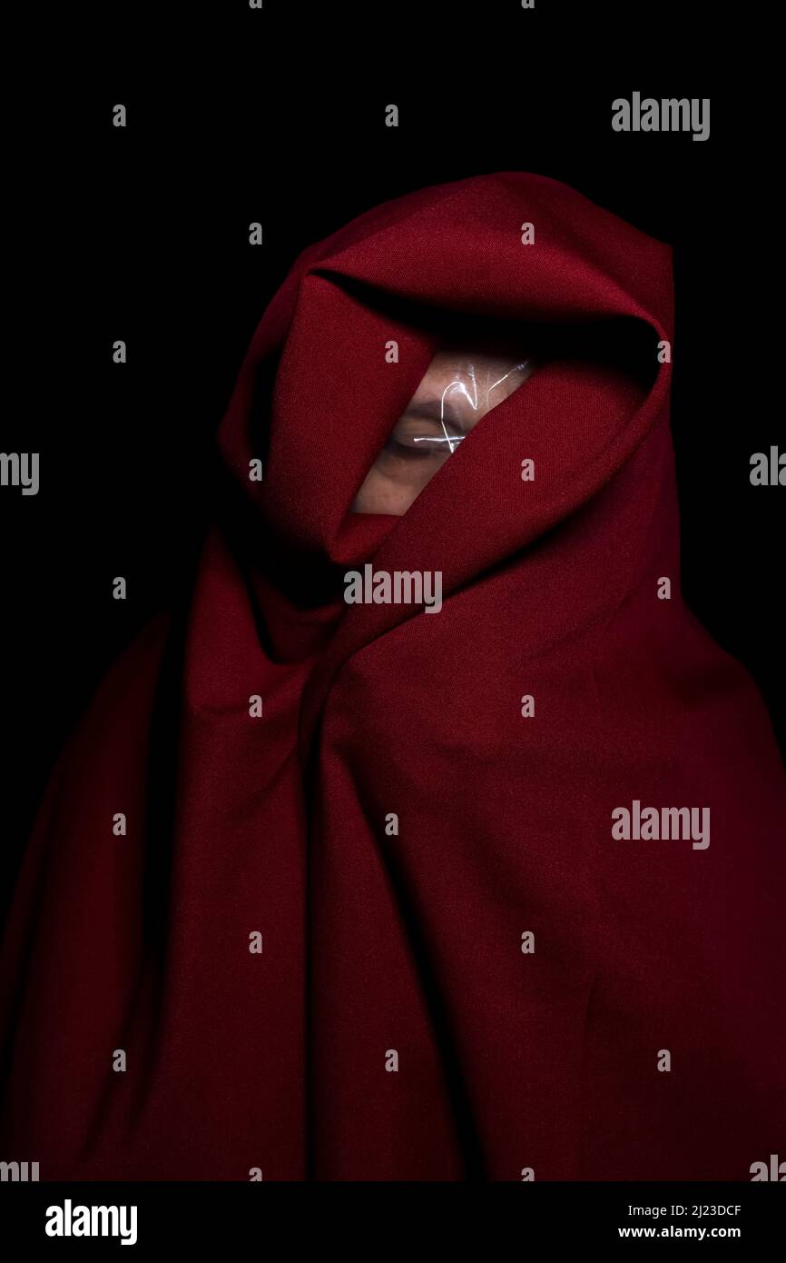 Man covered in red cloth with plastic on his face against black ...