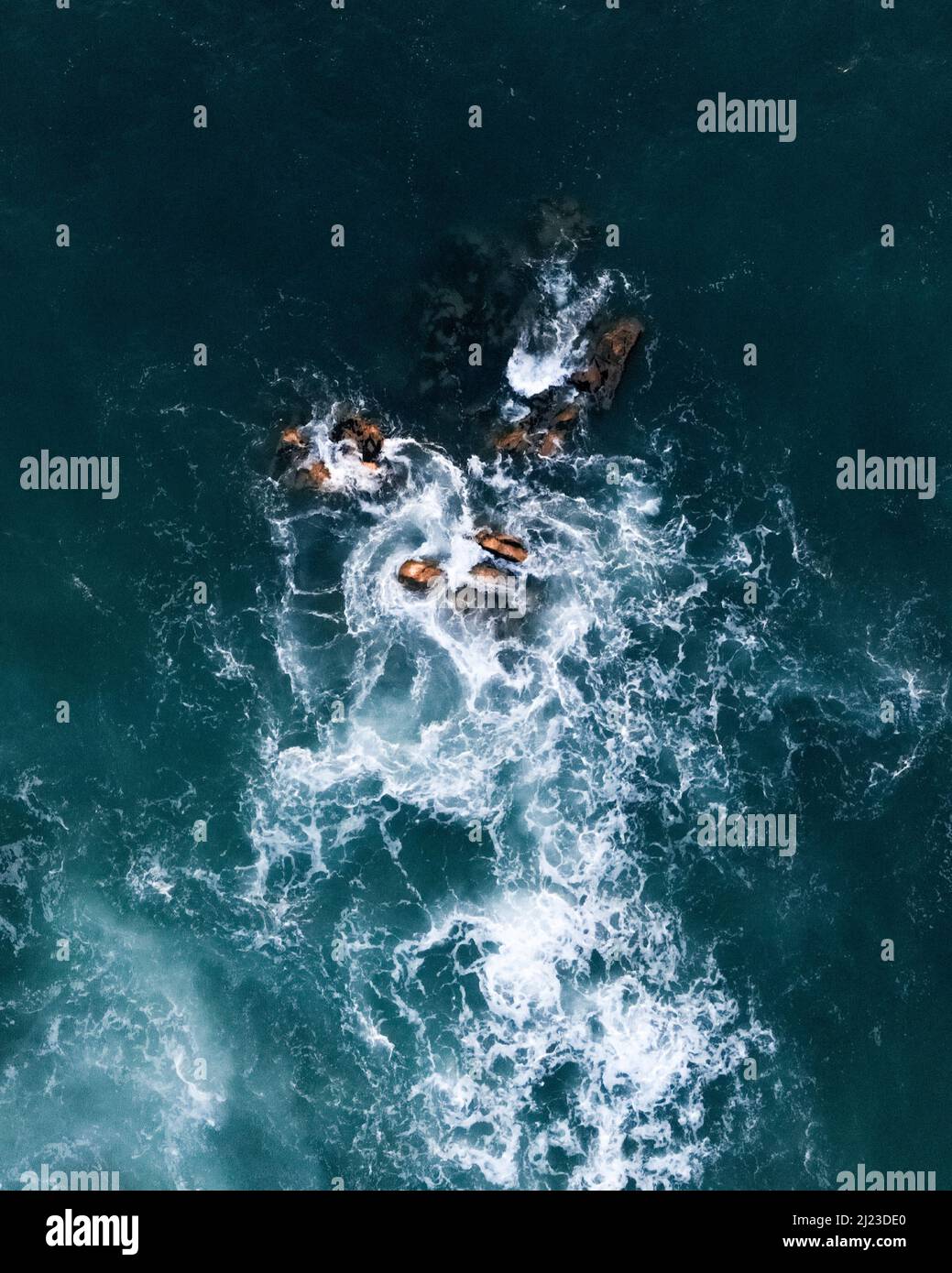 An aerial vertical shot of a body of water with waves hitting the giant ...