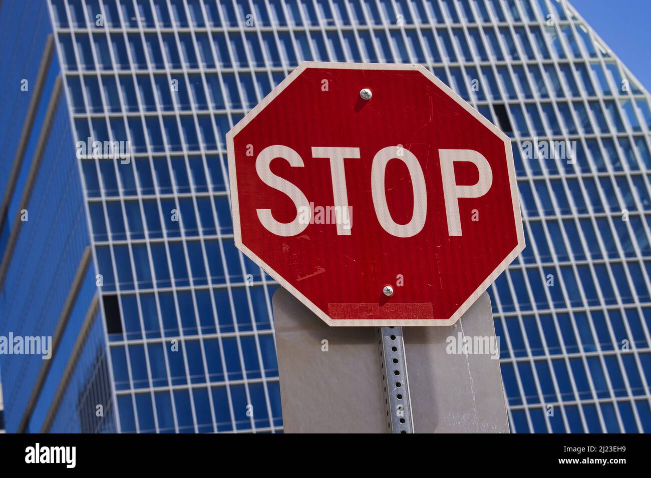 A closeup of a stop sign and a skyscraper in the background Stock Photo ...