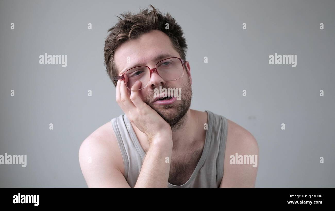 Caucasian unkempt man in glasses having headache after party. Being ...