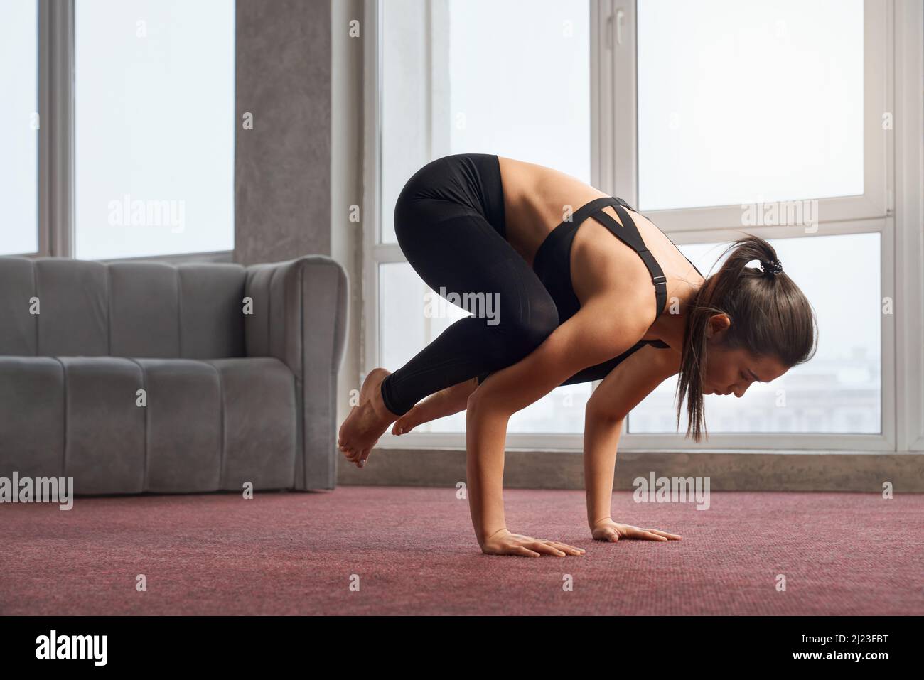 Side view of young sporty female practicing yoga pose indoors. Brunette ...