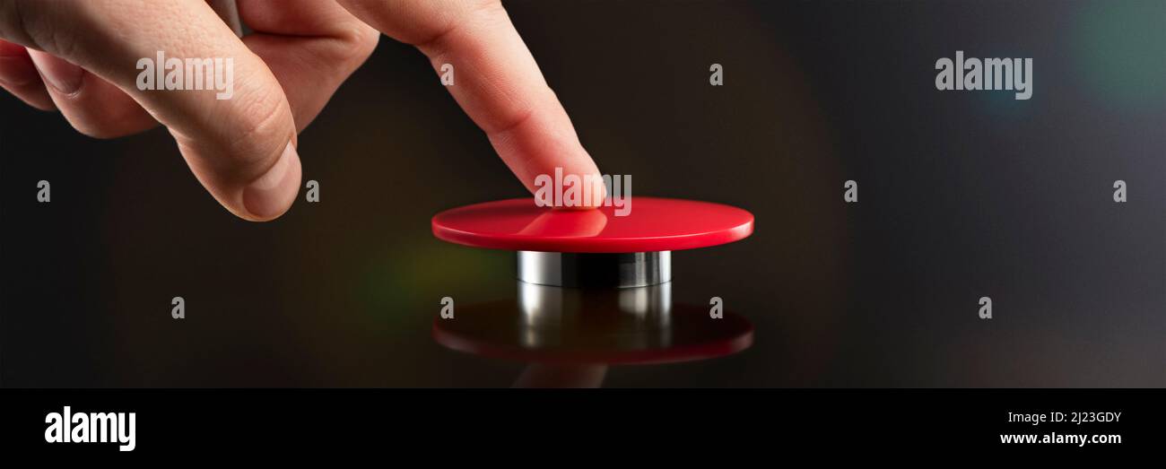A man's hand presses a big red button. Red button on a dark background ...