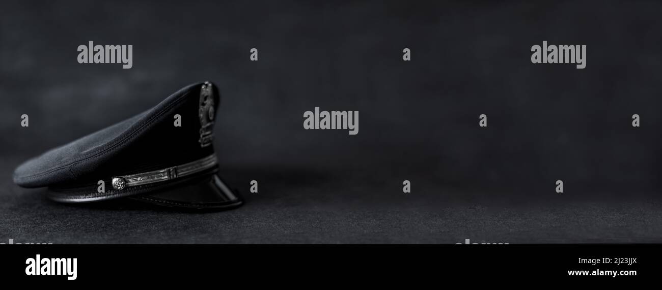A navy blue police hat cap in front of a navy blue background with copy ...