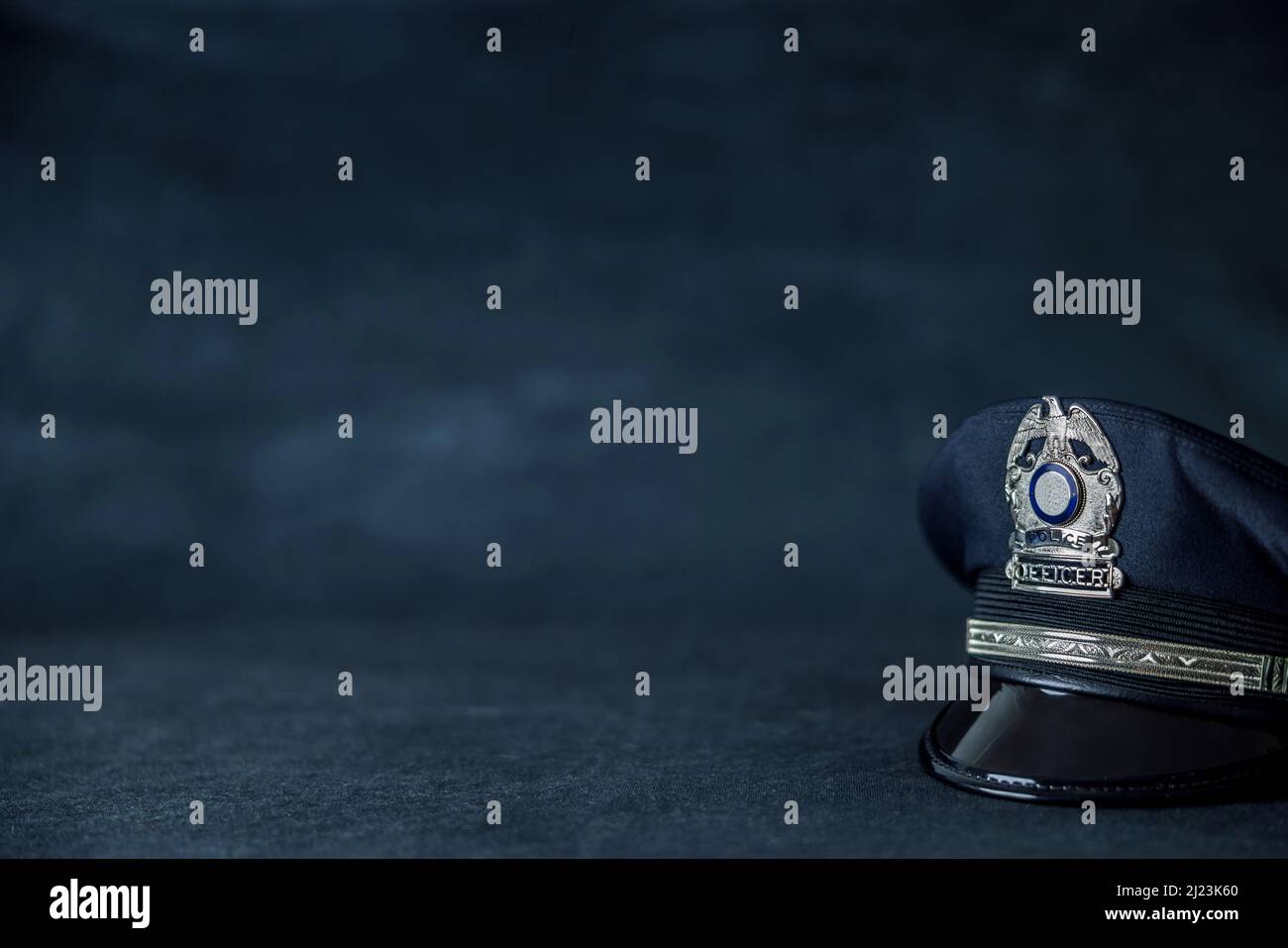 A navy blue police hat cap in front of a navy blue background with copy ...