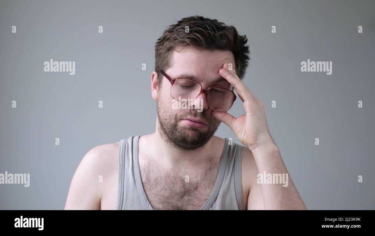 Young tired man in huge glasses under stress having troubles with ...