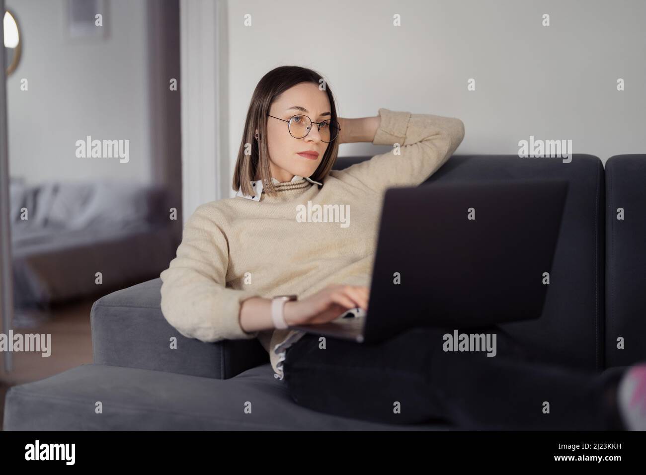 Caucasian Woman using laptop while sitting on the sofa at home in the ...