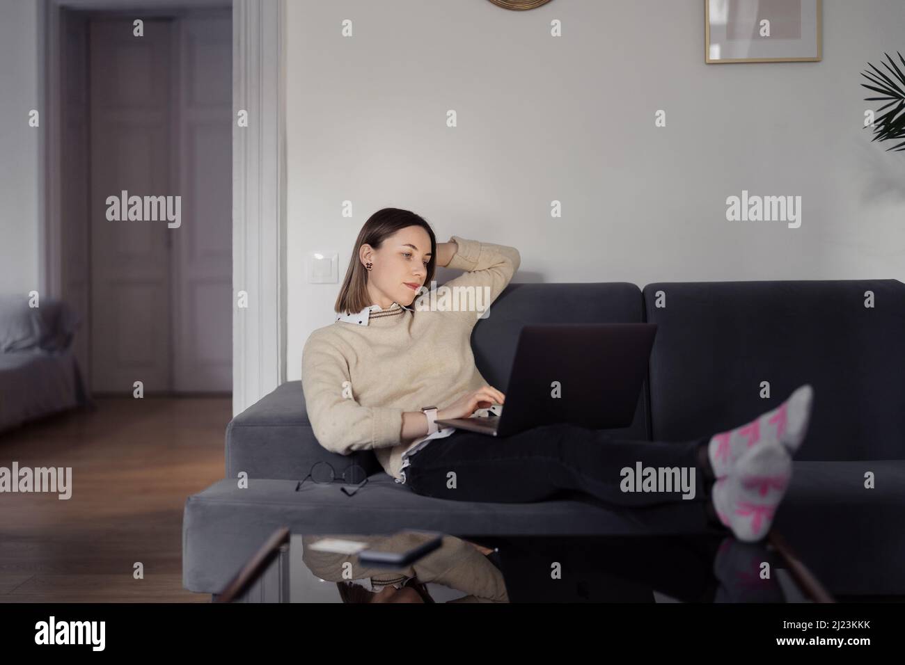Caucasian Woman using laptop while lying on the sofa at home in the ...
